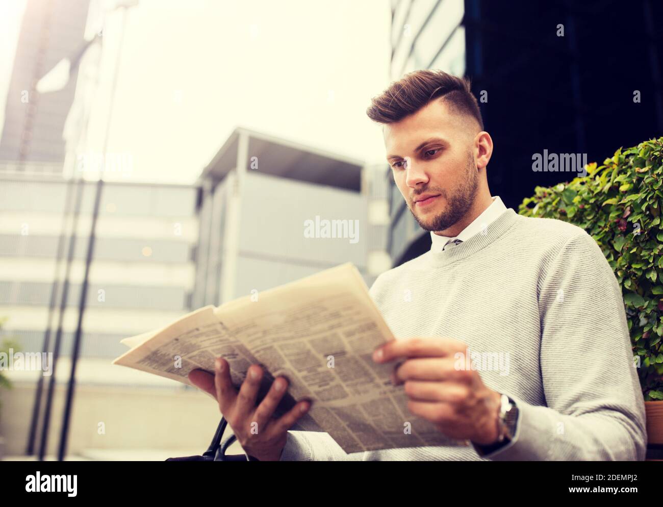 man reading newspaper on city street bench Stock Photo - Alamy