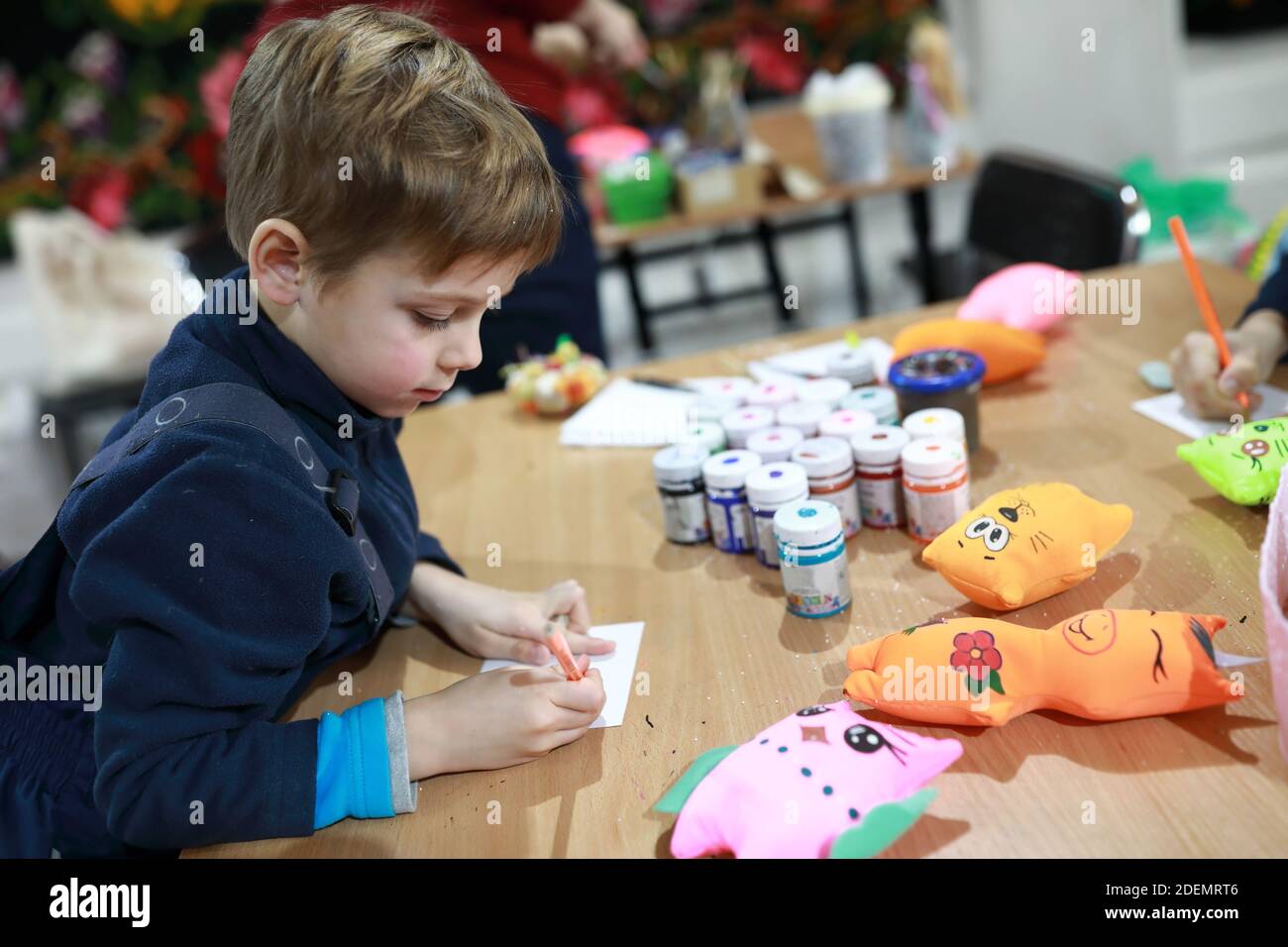 Child drawing soft toy design on sheet of paper in workshop Stock Photo ...