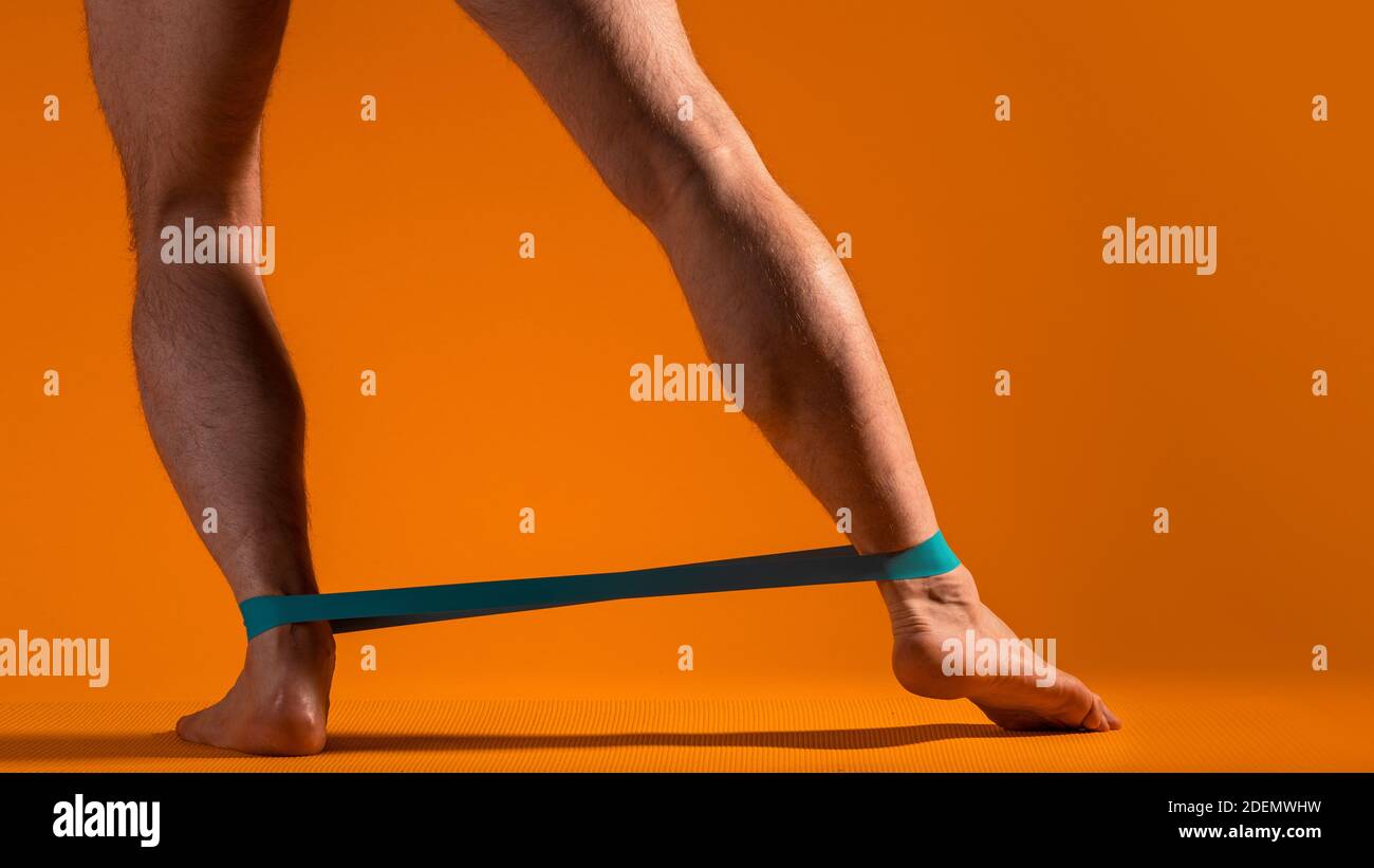Muscular men's legs with elastic band for fitness, do exercises to ...