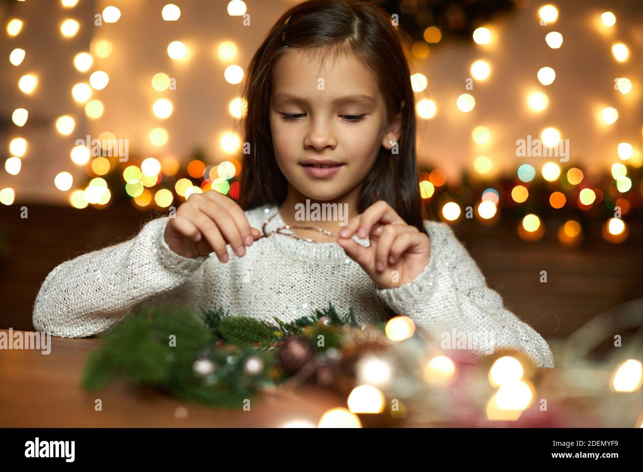 happy cute little child girl makes a handmade Christmas wreath at home ...