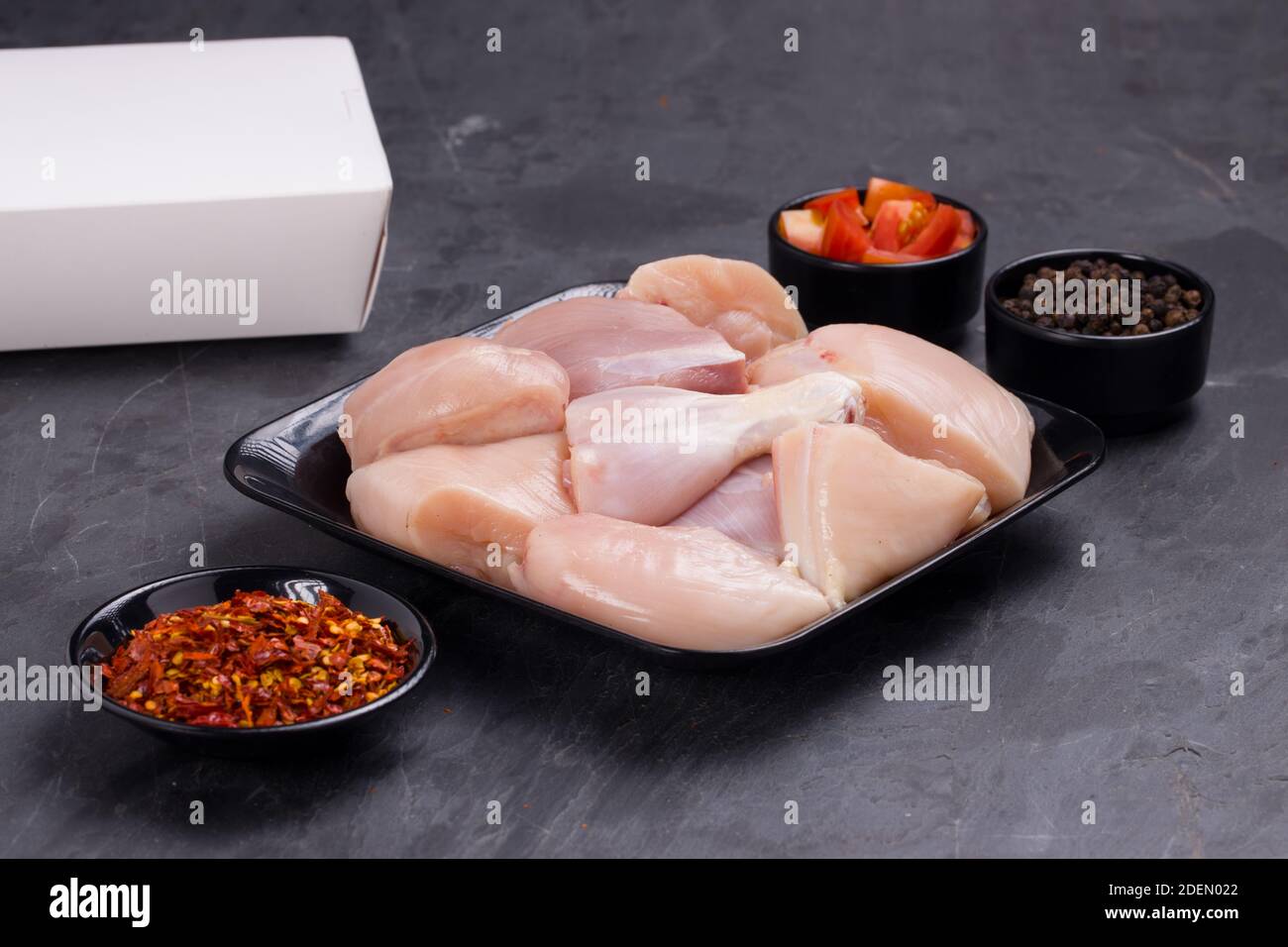 Raw chicken tender curry cut without skin arranged on black plate and ...