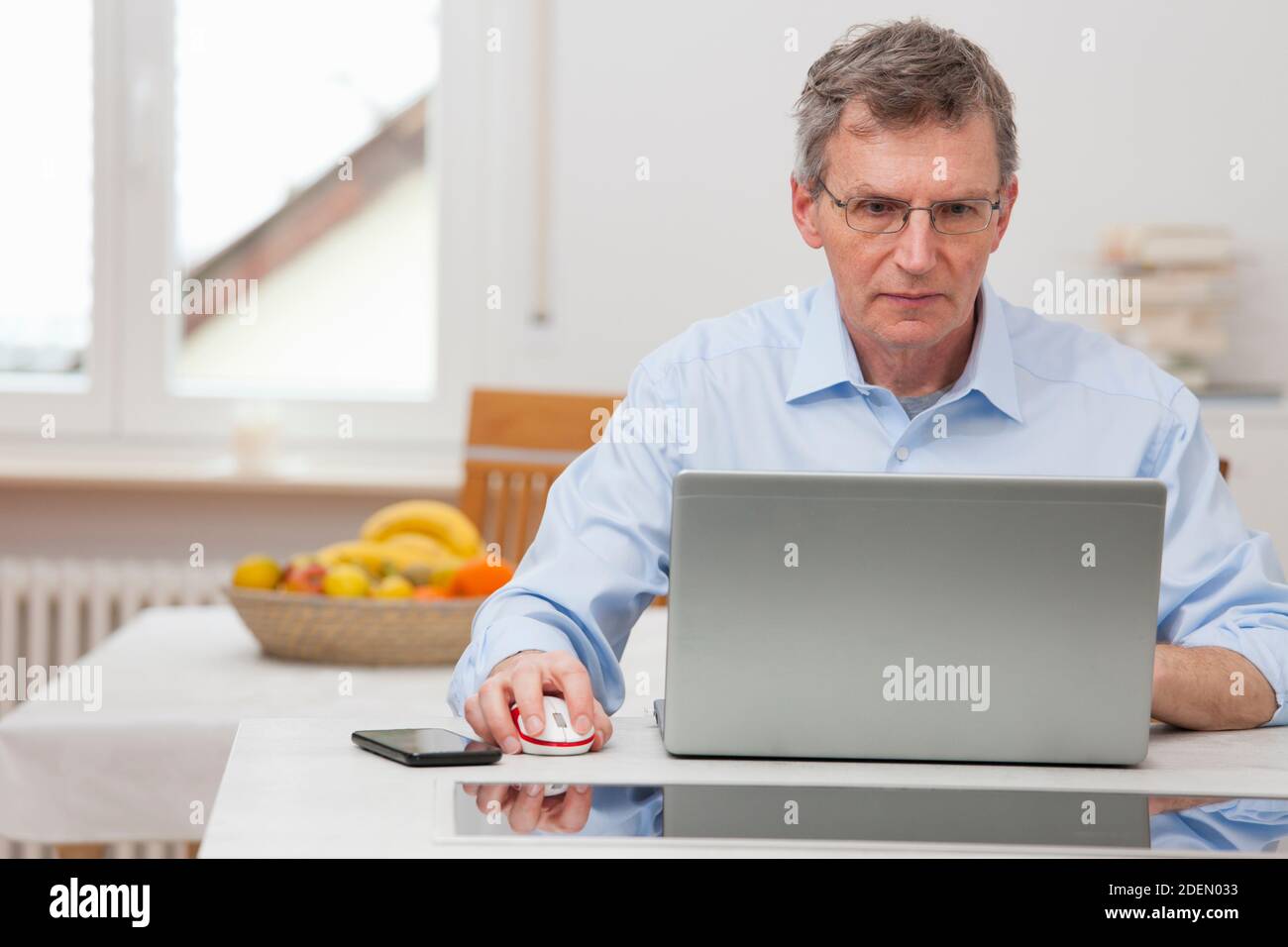 Mature businessman working remote with laptop at home - focus on the ...