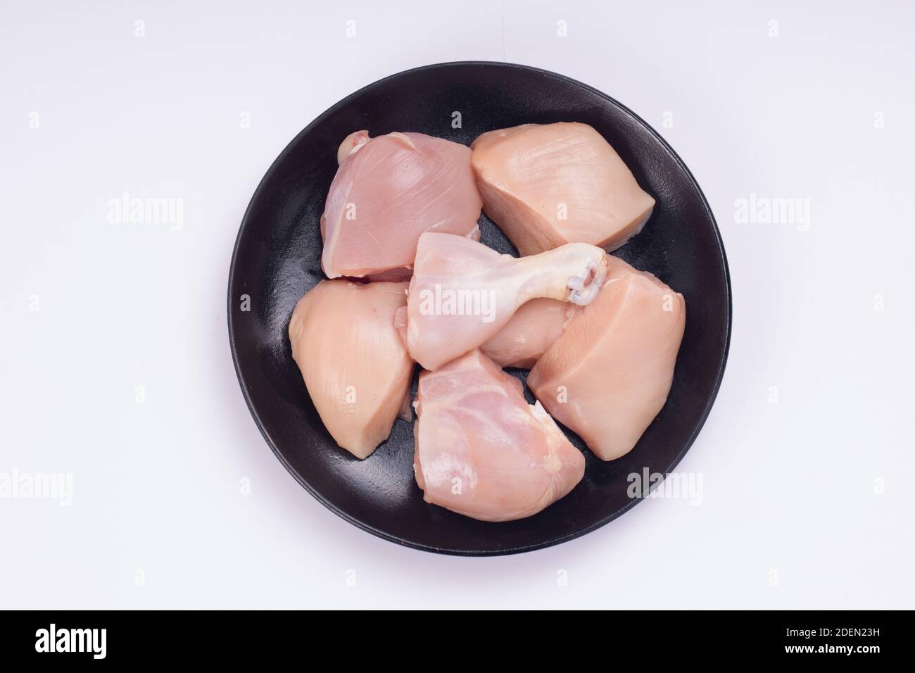 Raw chicken tender curry cut without skin arranged on black plate with ...
