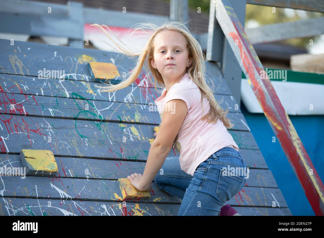 A little girl is climbing a rock climbing wall. The child plays on the ...