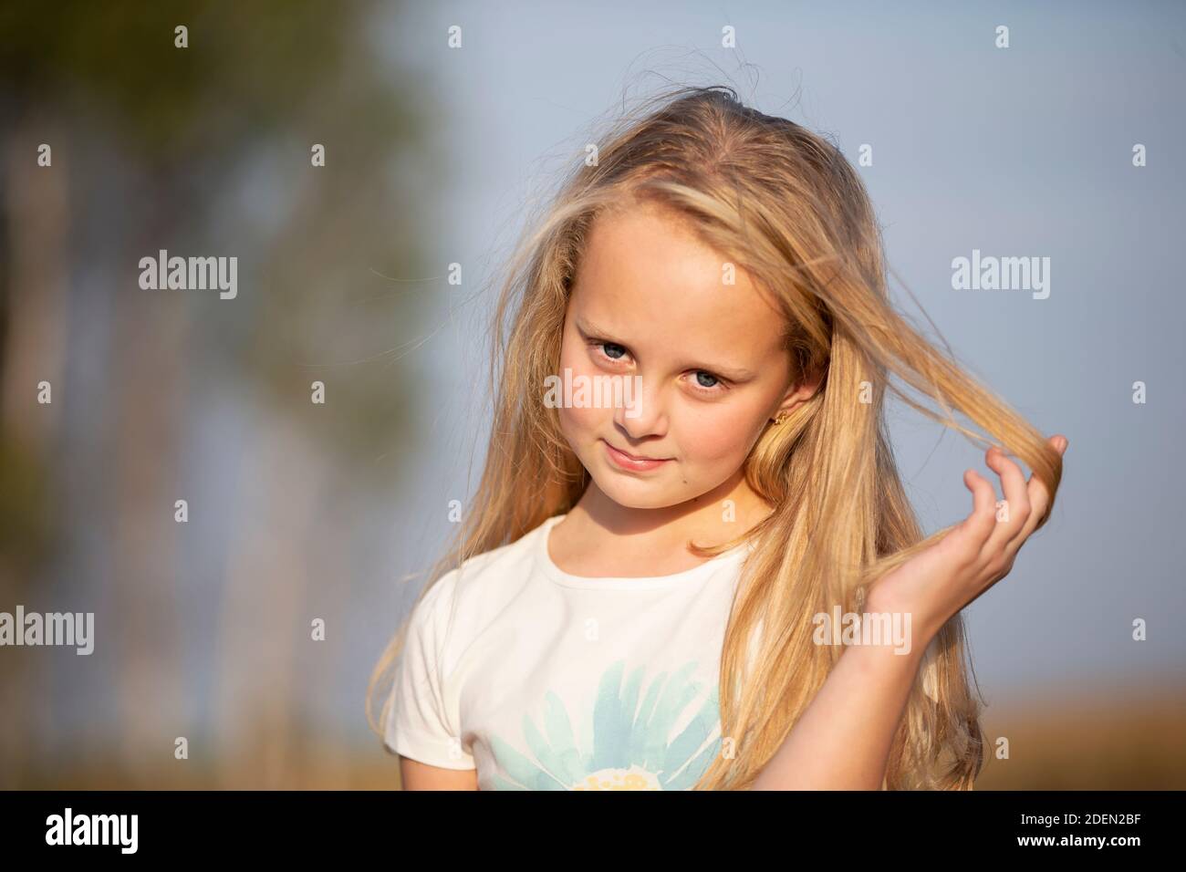 Beautiful little blonde girl on a background of blue sky Stock Photo ...