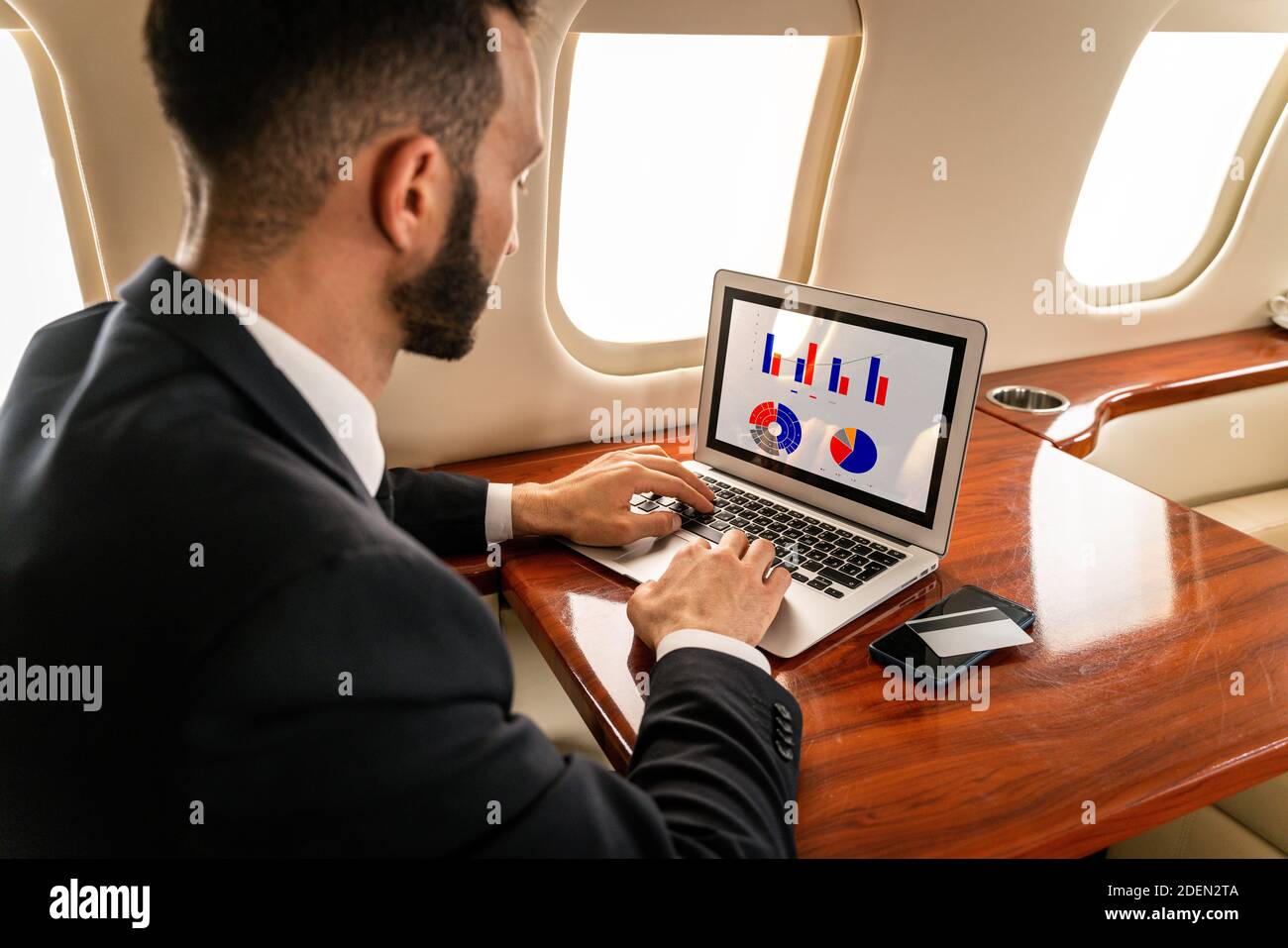 Handsome businessman wearing elegant suit flying on exclusive private ...