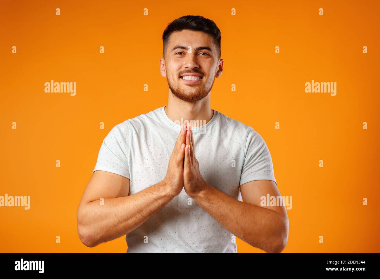 Relaxed man standing in meditating pose against yellow background Stock ...