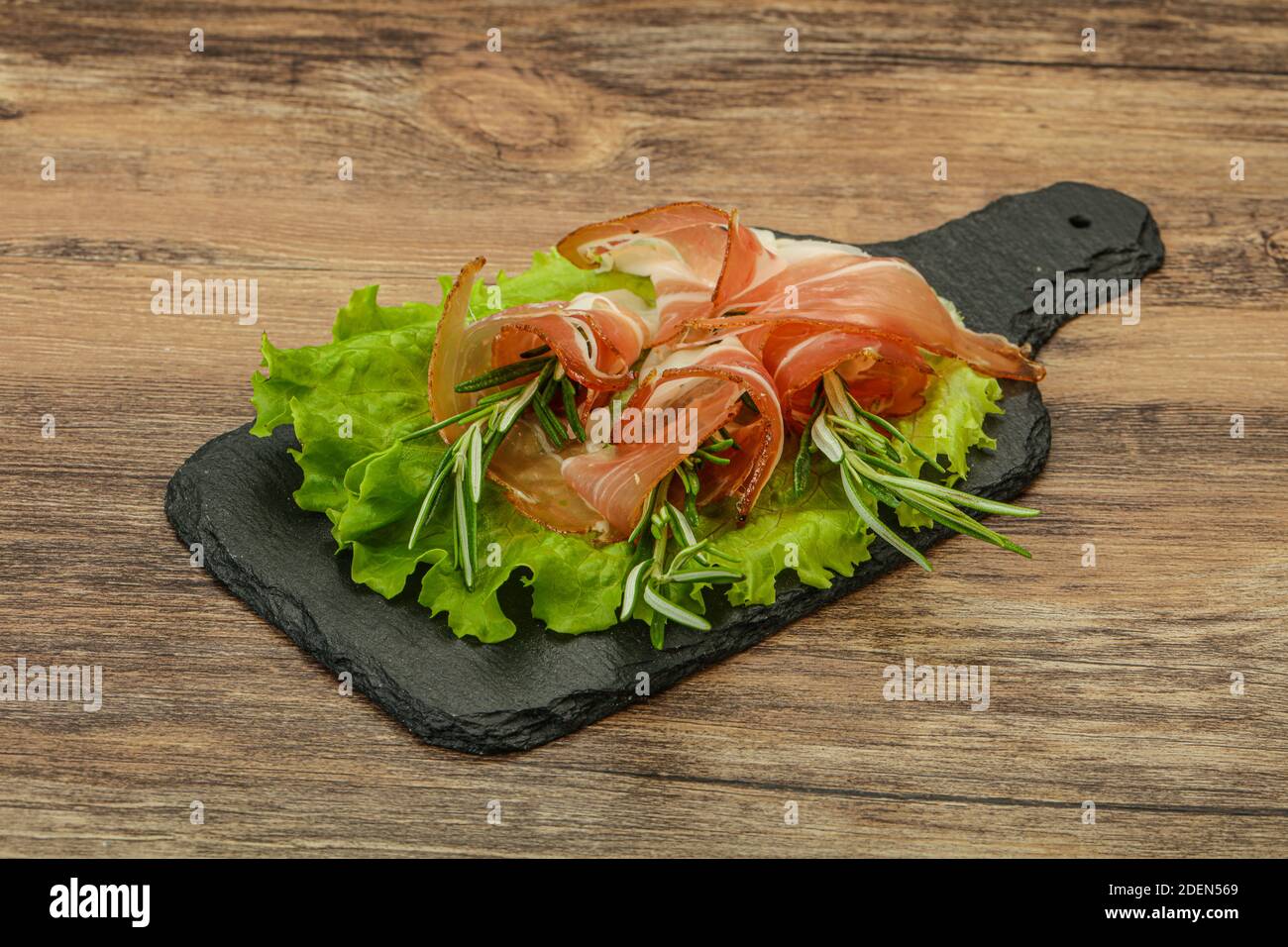 Sliced pork Jamon meat with rosemary Stock Photo - Alamy