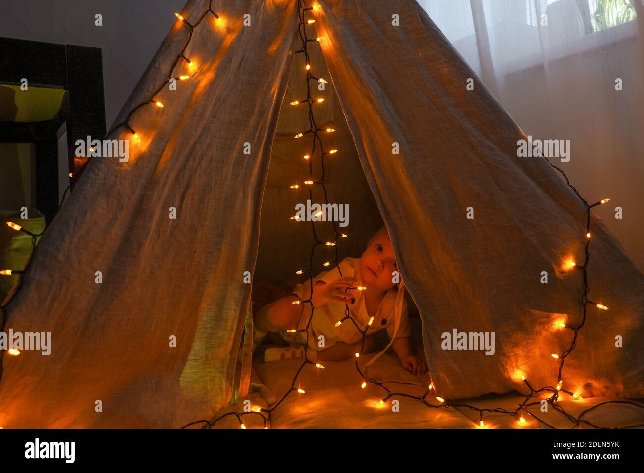 Magic wigwam with garlands and lights with cute little girl inside ...