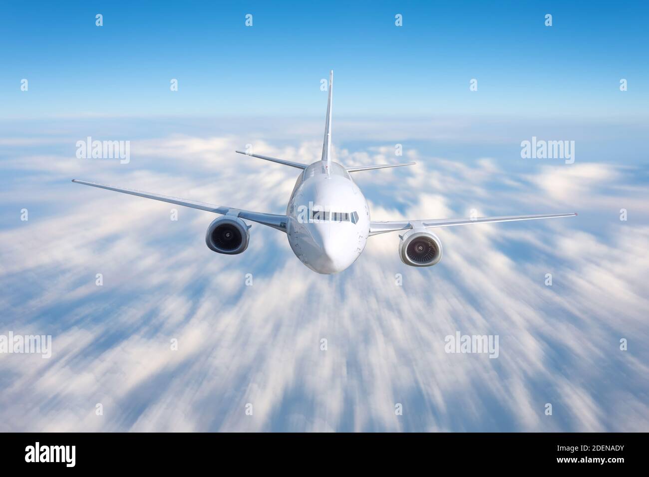 Airplane flies rapidly above the clouds high in the sky, the front view ...