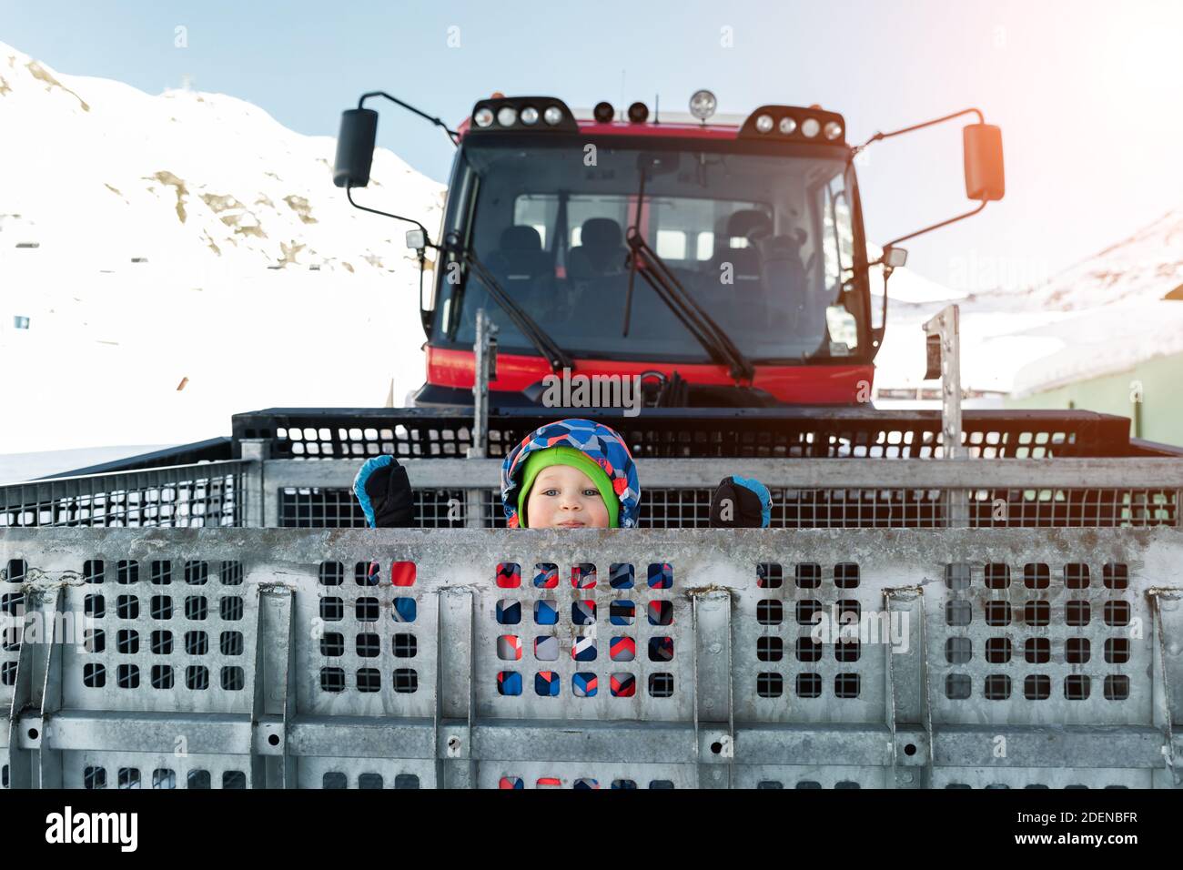 Cute adorable playful happy toddler boy inside red modern snowcat ...