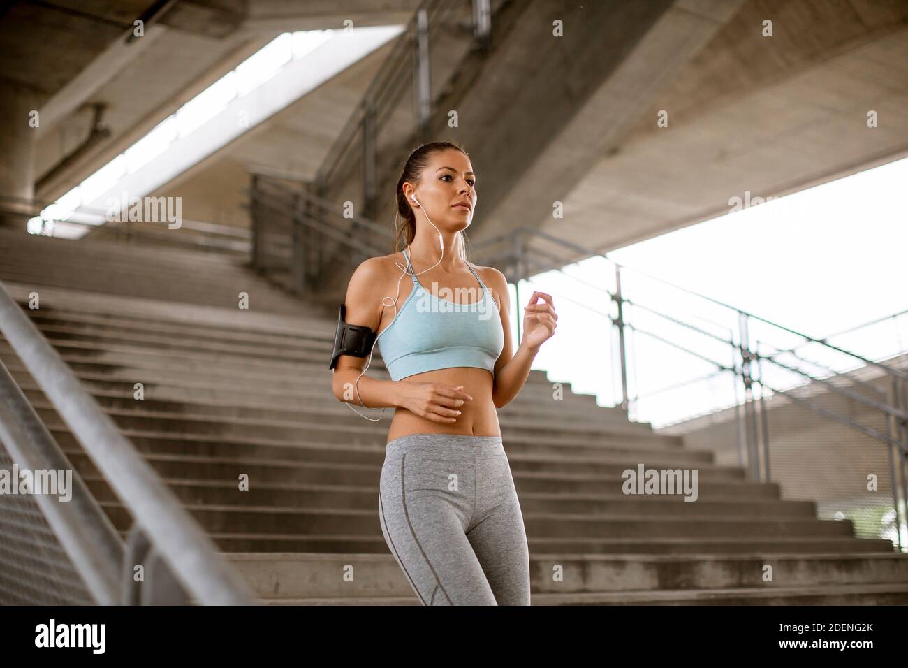Pretty young woman running down the stairs in the urban environment ...