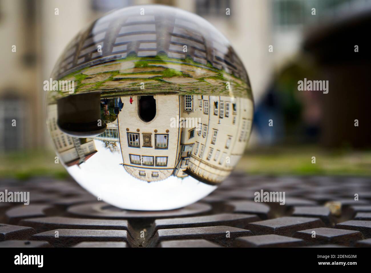 Upside down large building in a glass ball on a stone parapet, blurred ...