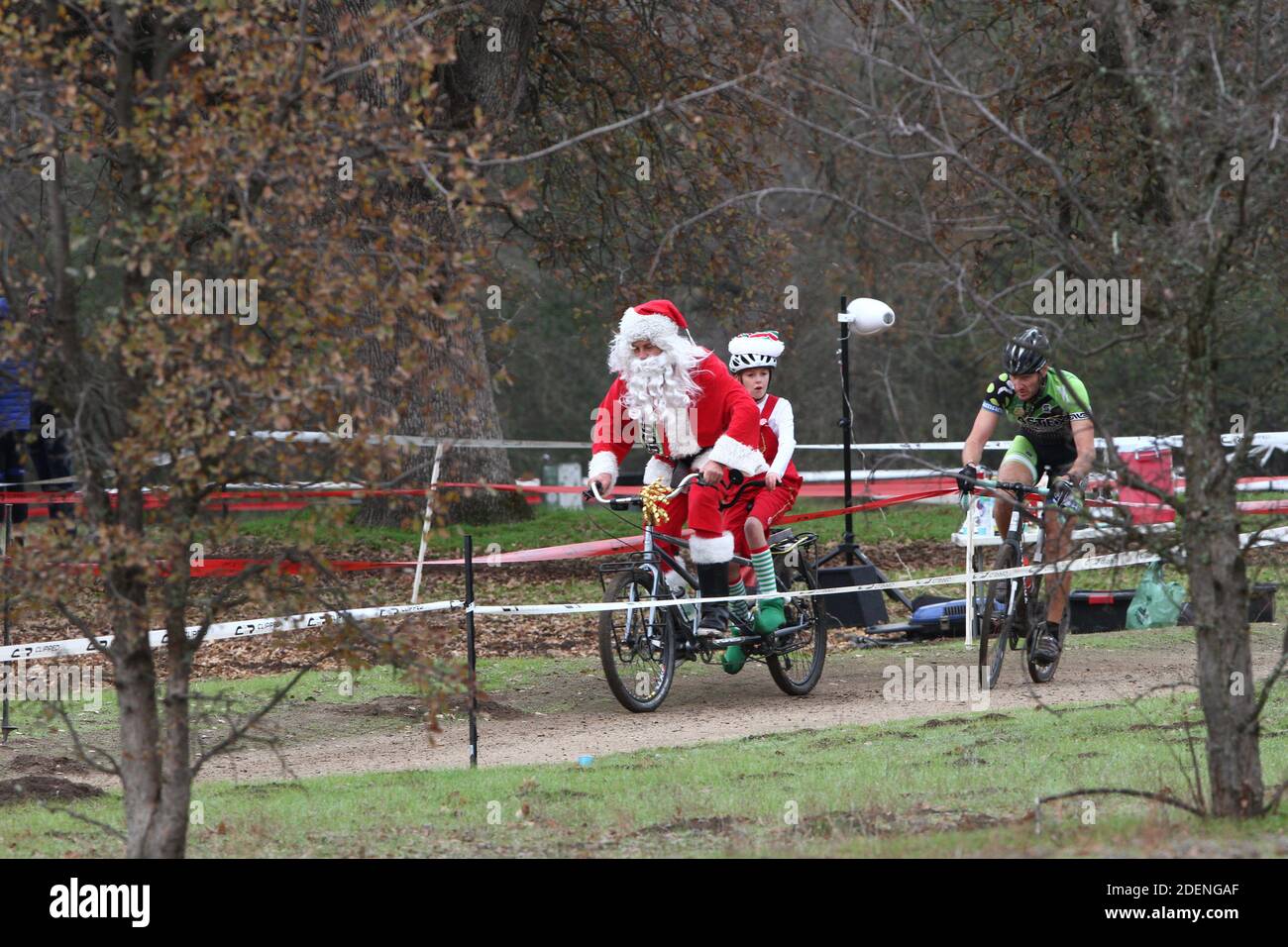 Santa riding a bike delivering presents with elf helper Stock Photo - Alamy