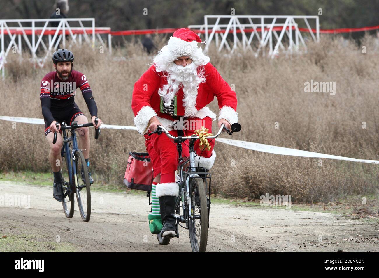 Santa riding a bike delivering presents with elf helper Stock Photo - Alamy