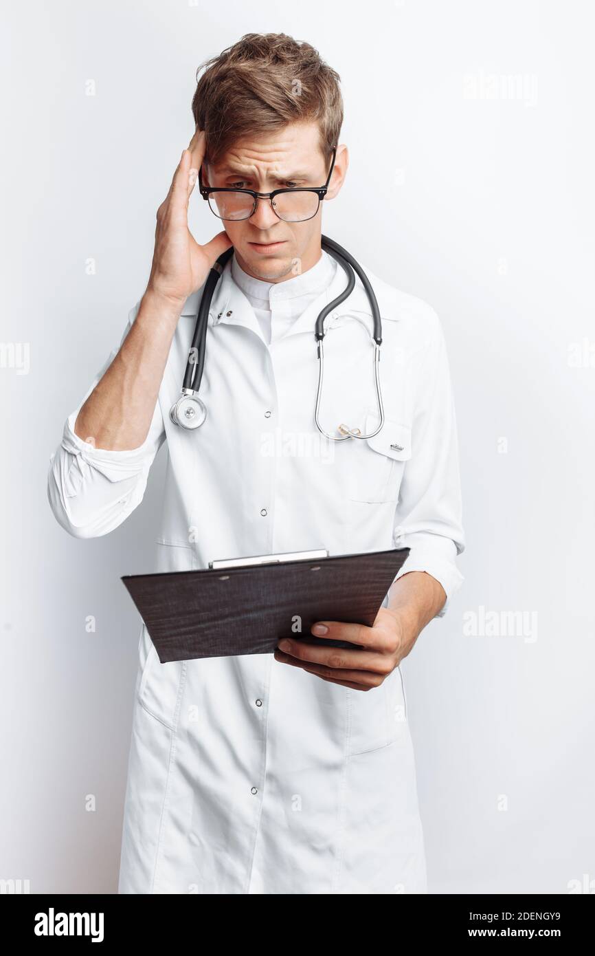 Thoughtful doctor, looking at the documents, and makes notes in the ...