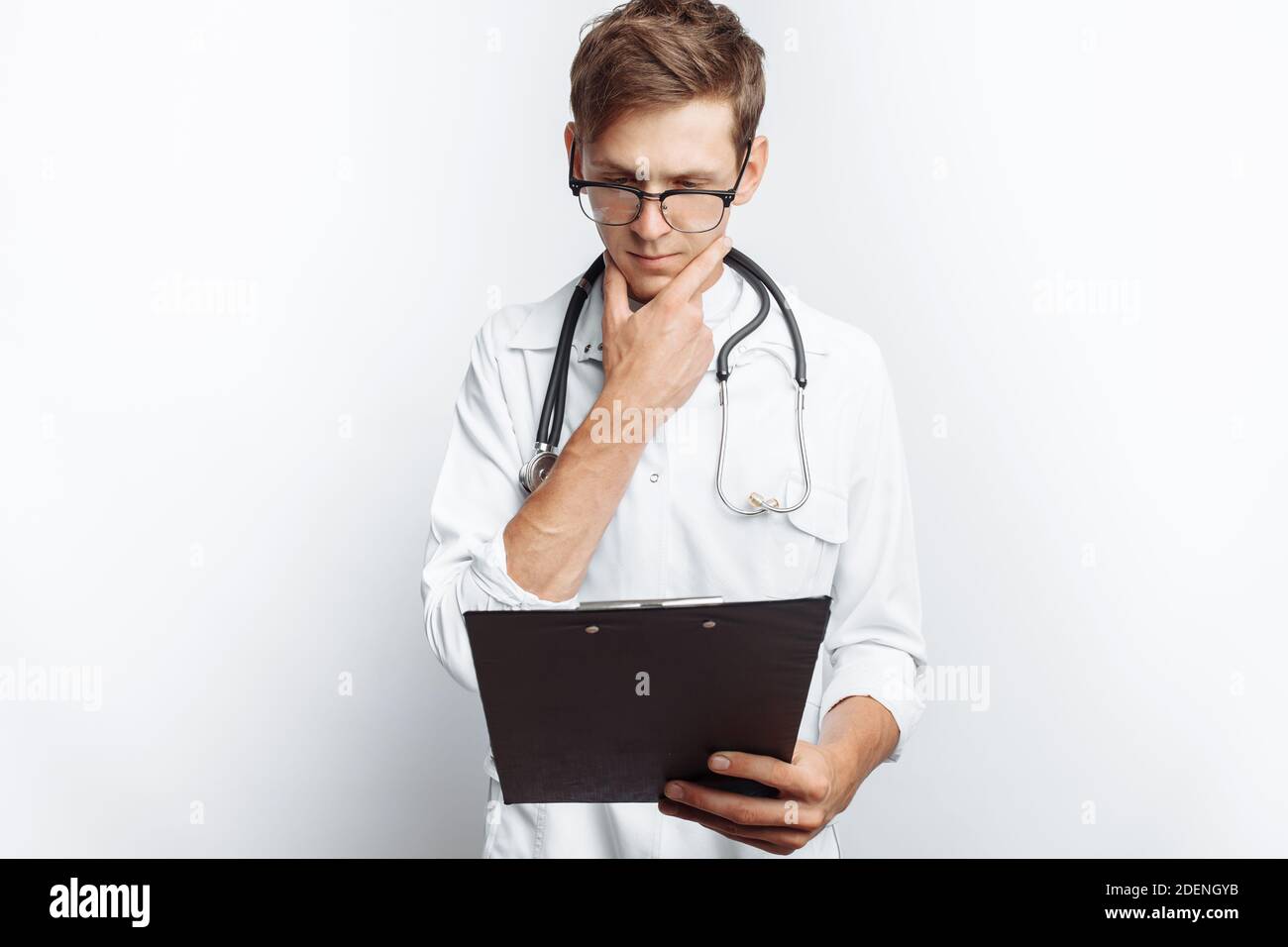 Thoughtful doctor, looking at the documents, and makes notes in the ...