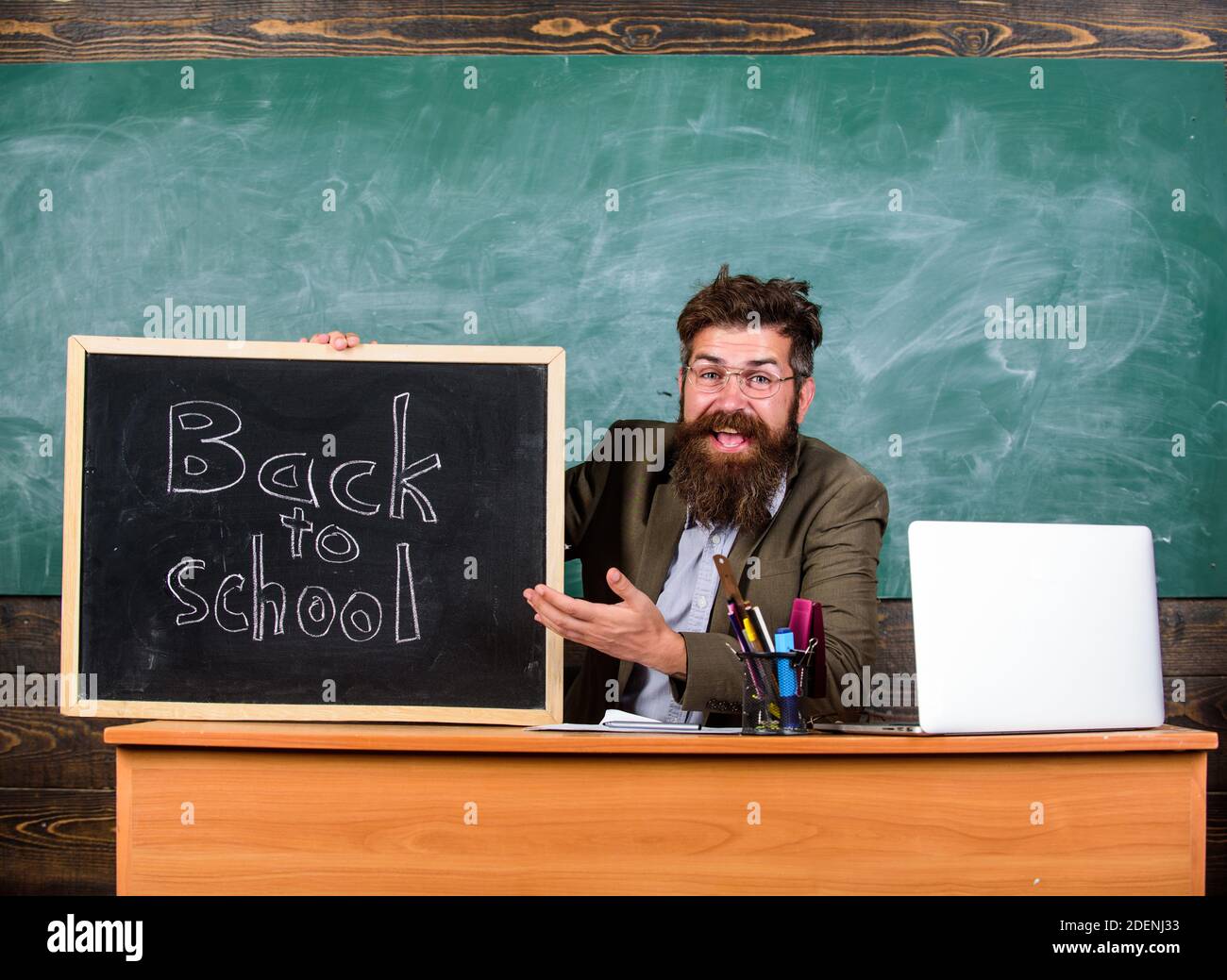 Teacher or school principal welcomes with blackboard inscription back ...