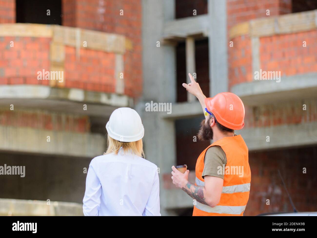 Discussing plan. Woman engineer and builder communicate at construction ...