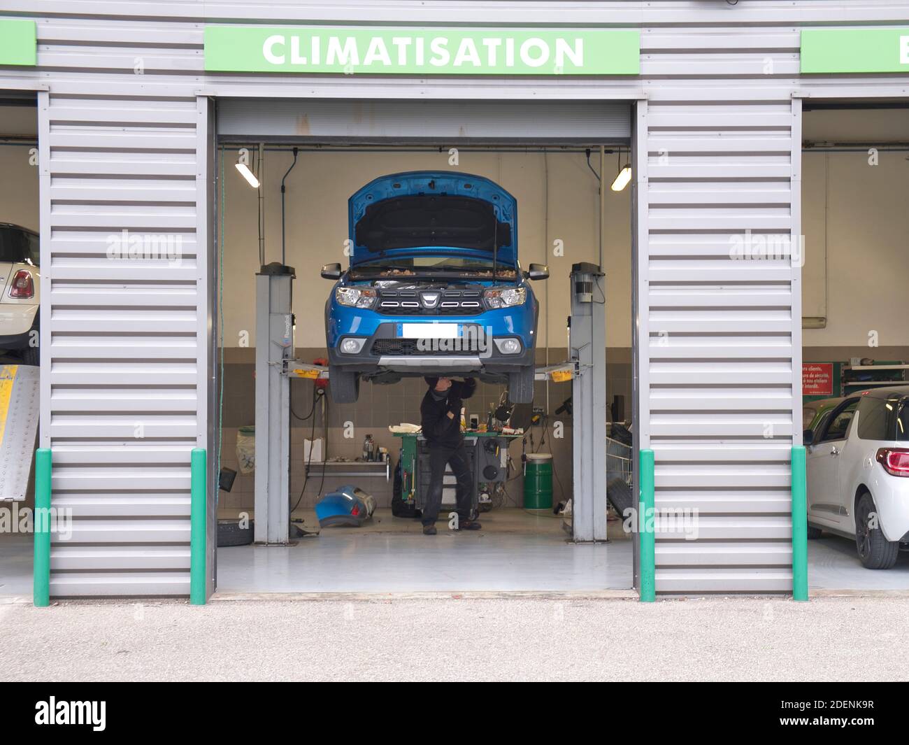 Service bay scene. Blue car with bonnet open raised on an inspection ...