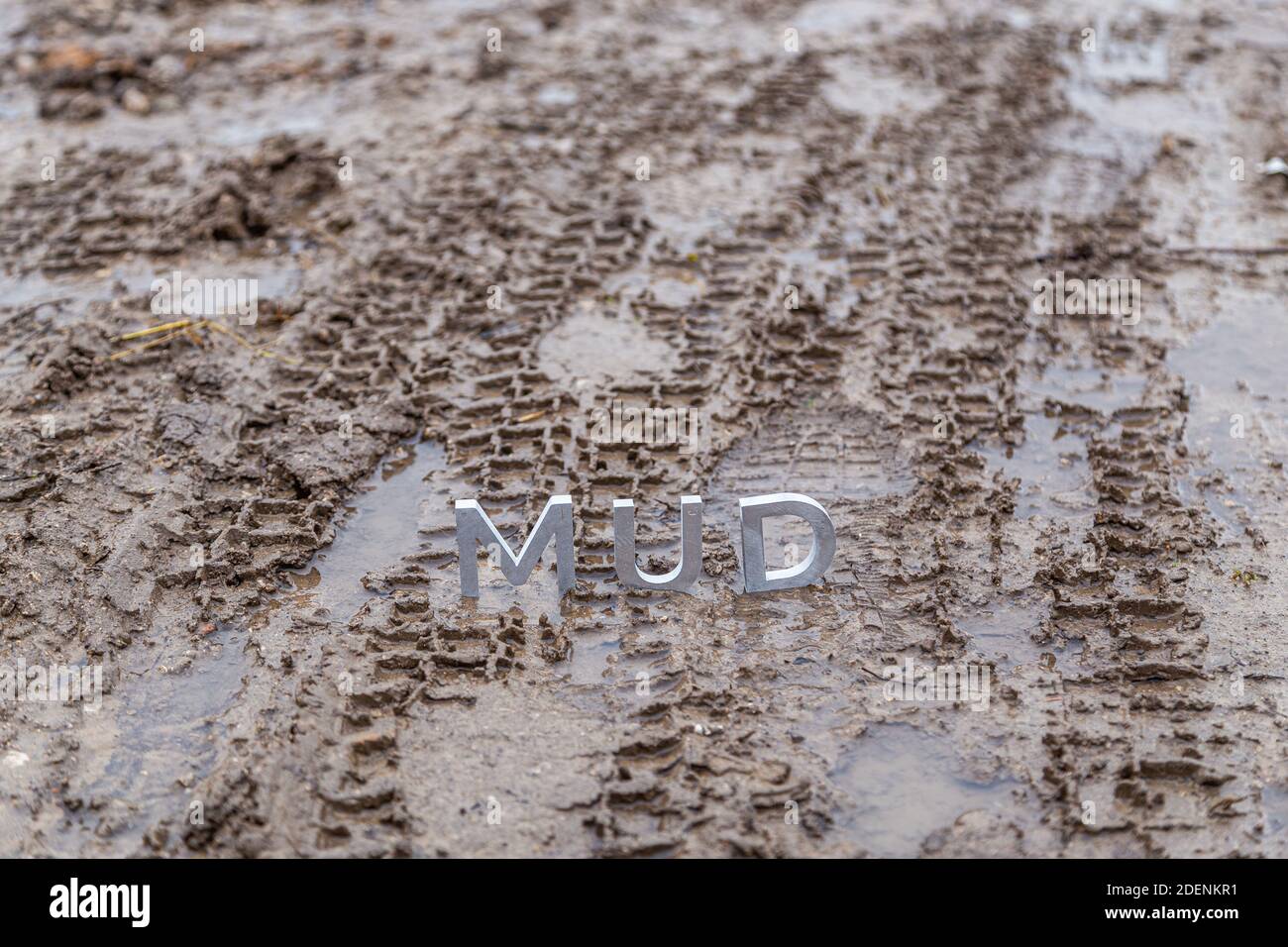 the word mud composed of silver metal letters on wet dirt surface Stock ...