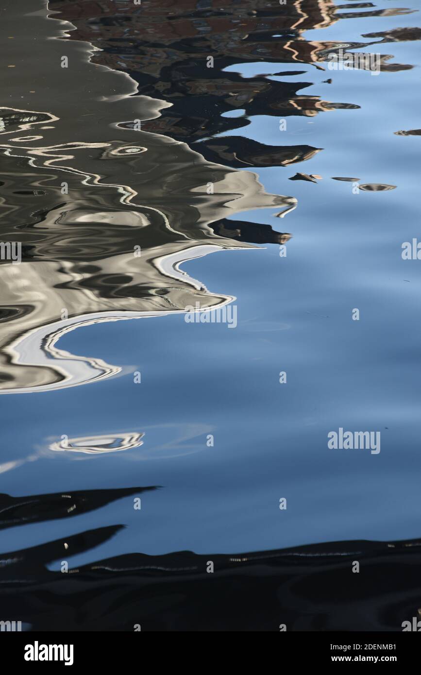 Reflections create abstract patterns in the water of an ocean harbour ...