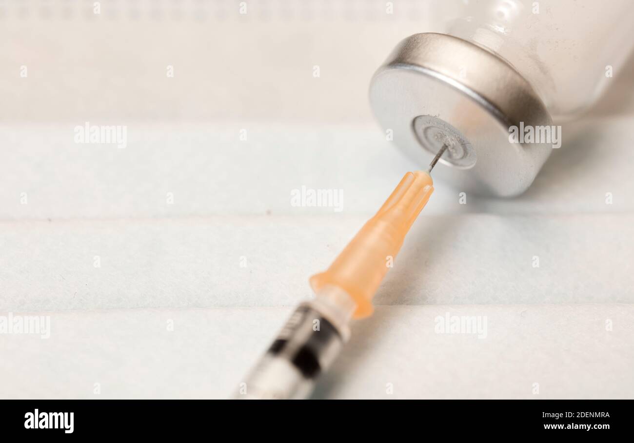 Vaccine vial with medical syringe cannula, on mask. Macro Stock Photo ...