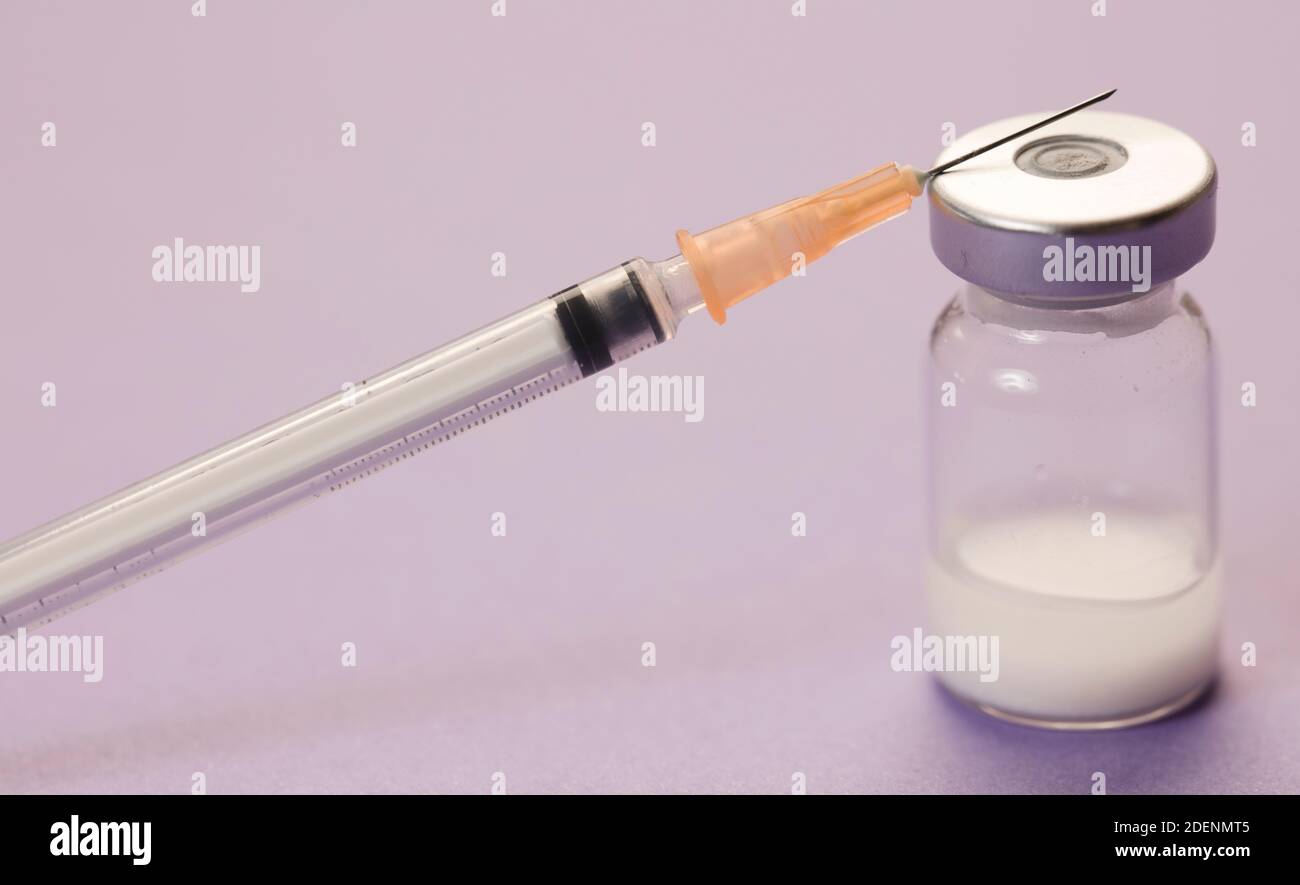 medical syringe cannula with vaccine vial, lilac background. macro ...