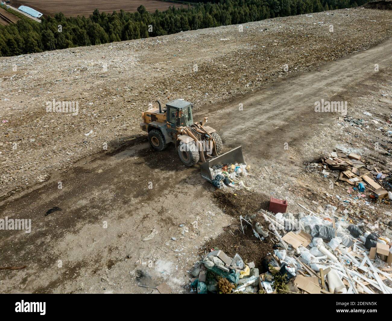 Top drone view of dump. Different types of garbage. Tractor carries ...