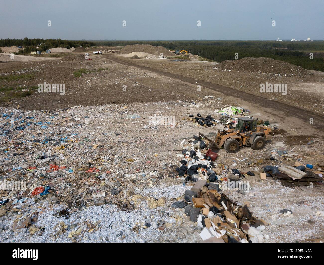 Top drone view of dump with different types of garbage. Tractor carries ...