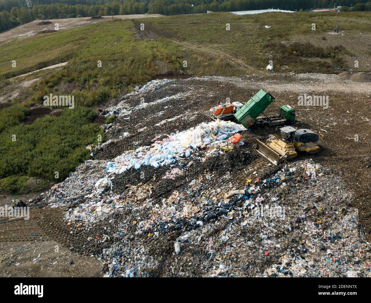 Top drone view of dump. Garbage truck unloading waste. Yellow tractor ...