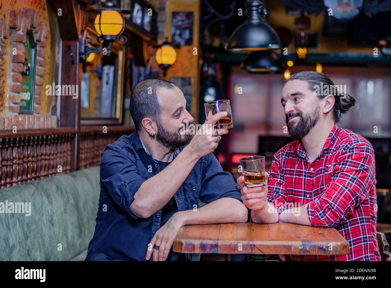 Two male friends drinking whiskey together at the pub. They are drunk ...