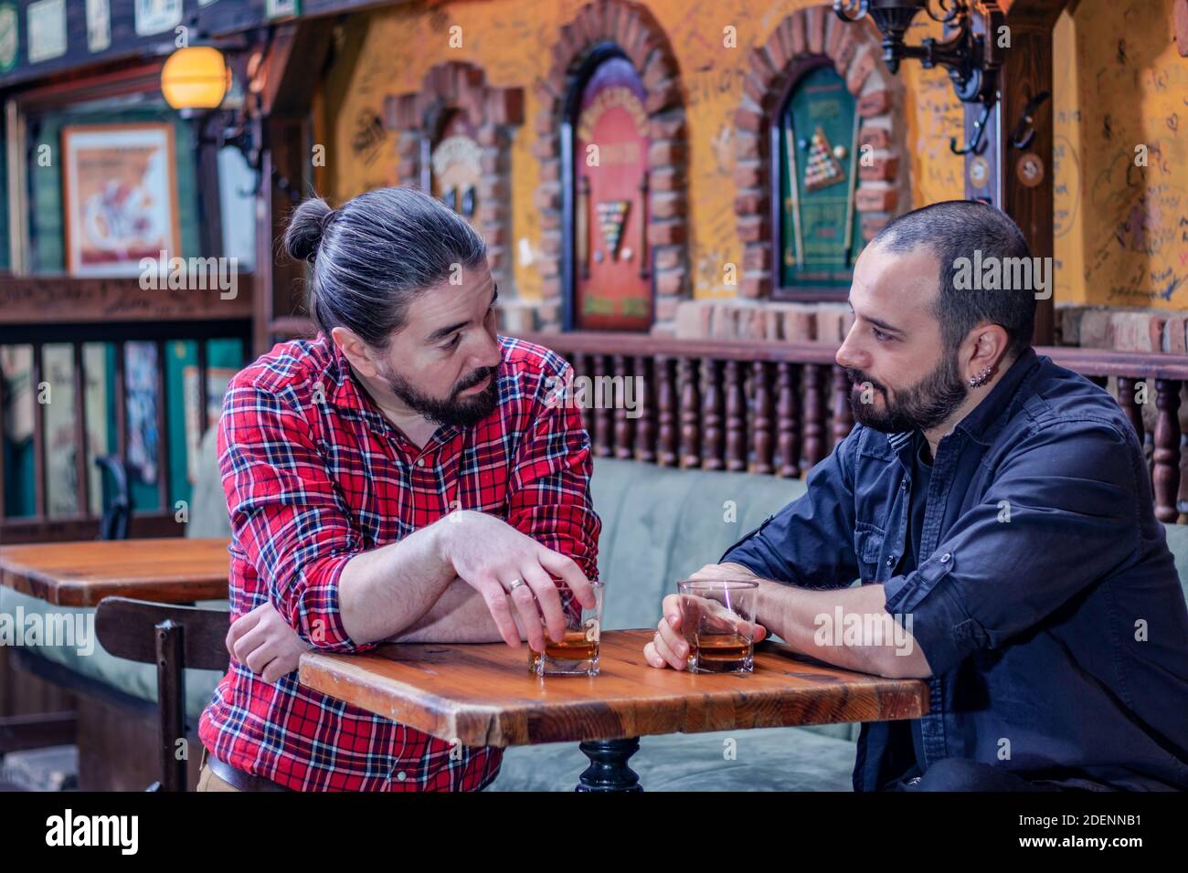 Two male friends drinking whiskey together at the pub. They are drunk ...