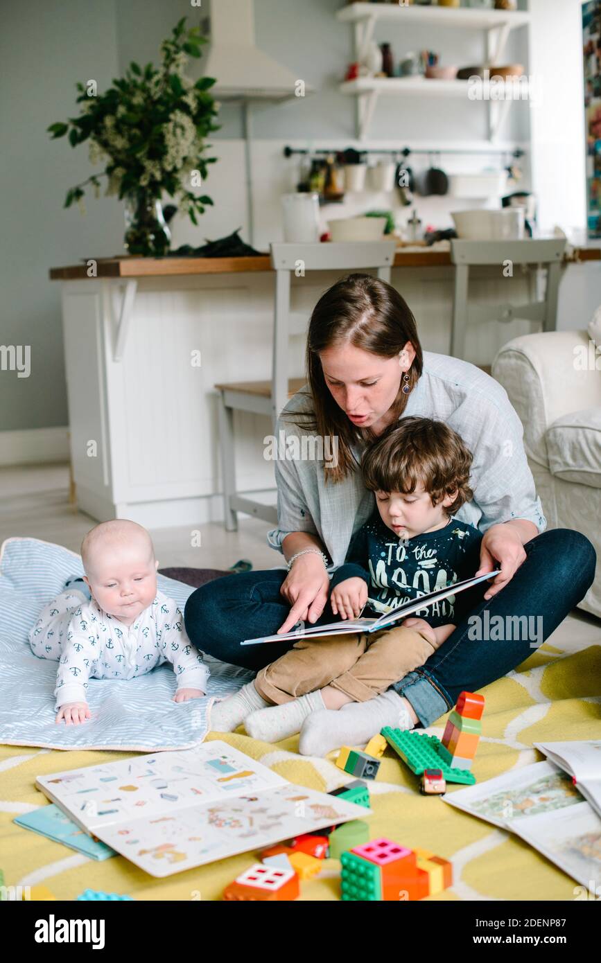Mother reading book with children sitting on the floor Stock Photo - Alamy