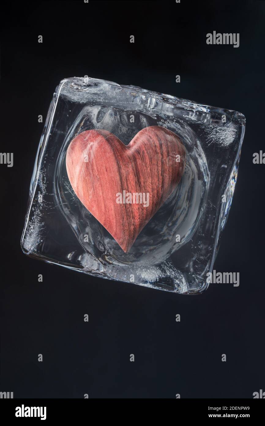 Heart inside ice cube on dark background. Cooling relations metaphor ...