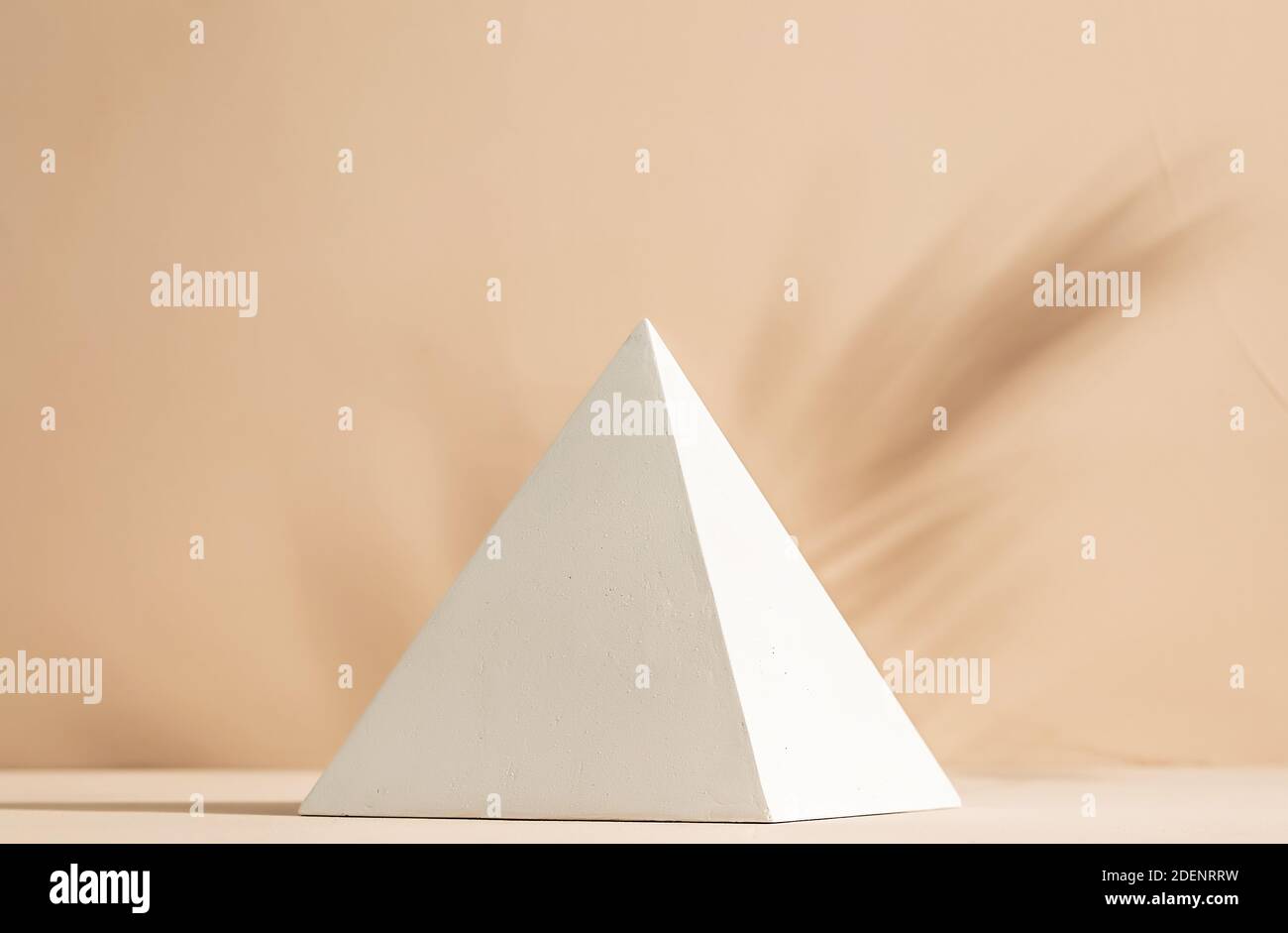 Gypsum pyramid in sunlight and palm leaf shadow on clay wall background ...