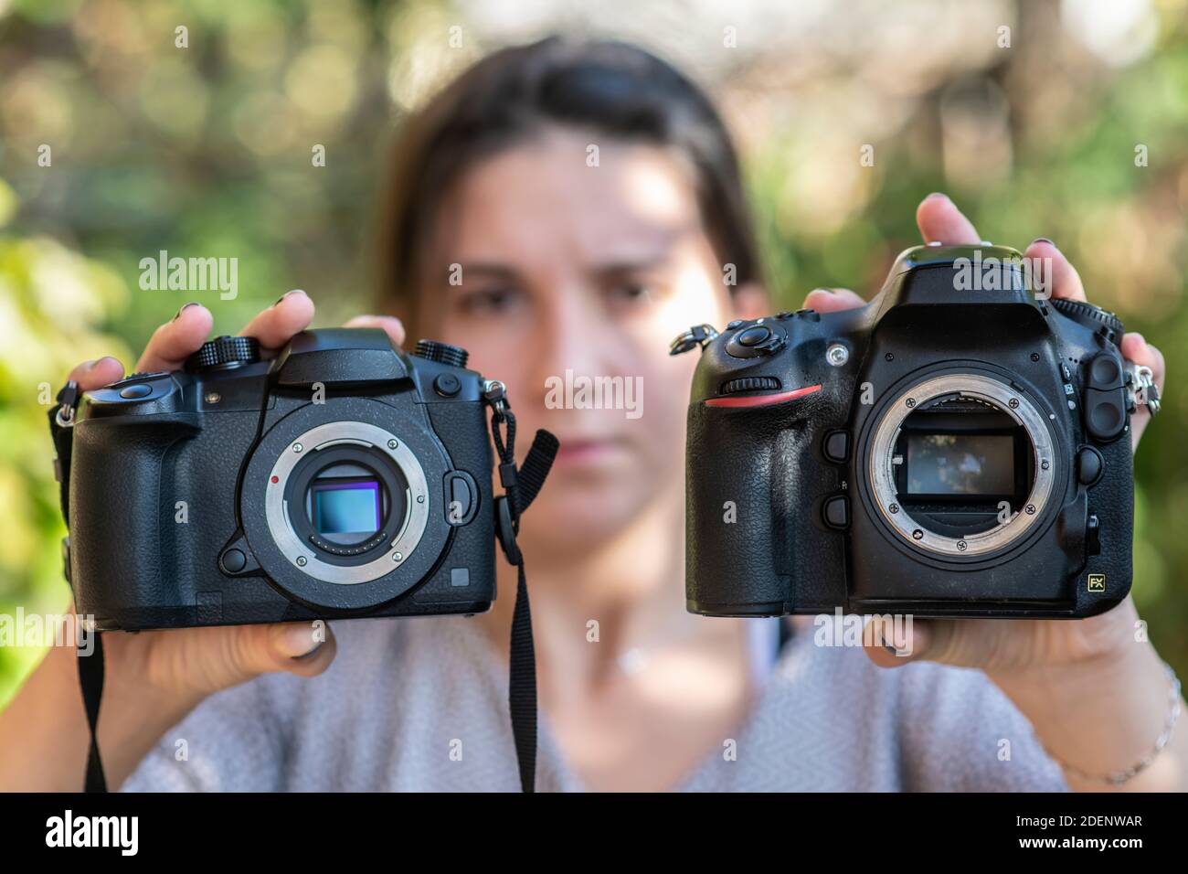 A girl holding mirrorless and DSLR camera with removed lenses and ...
