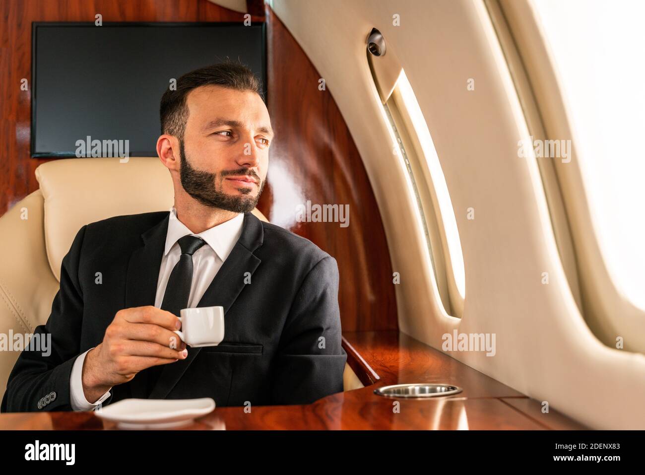 Handsome businessman wearing elegant suit flying on exclusive private ...