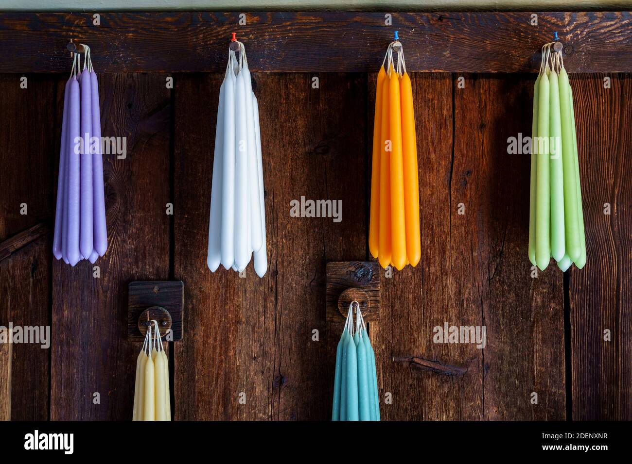 Colorful taper candles hanging against rustic wooden wall Stock Photo ...