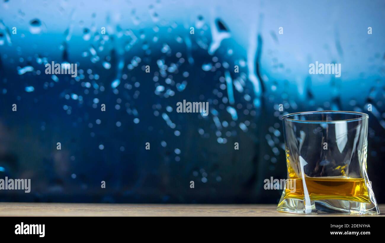 Whiskey in a glass against the background of a rainy window, background ...
