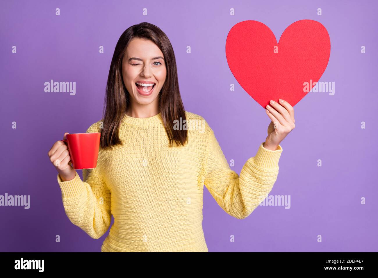 Photo portrait of winking girl holding big red cup heart card in hands ...