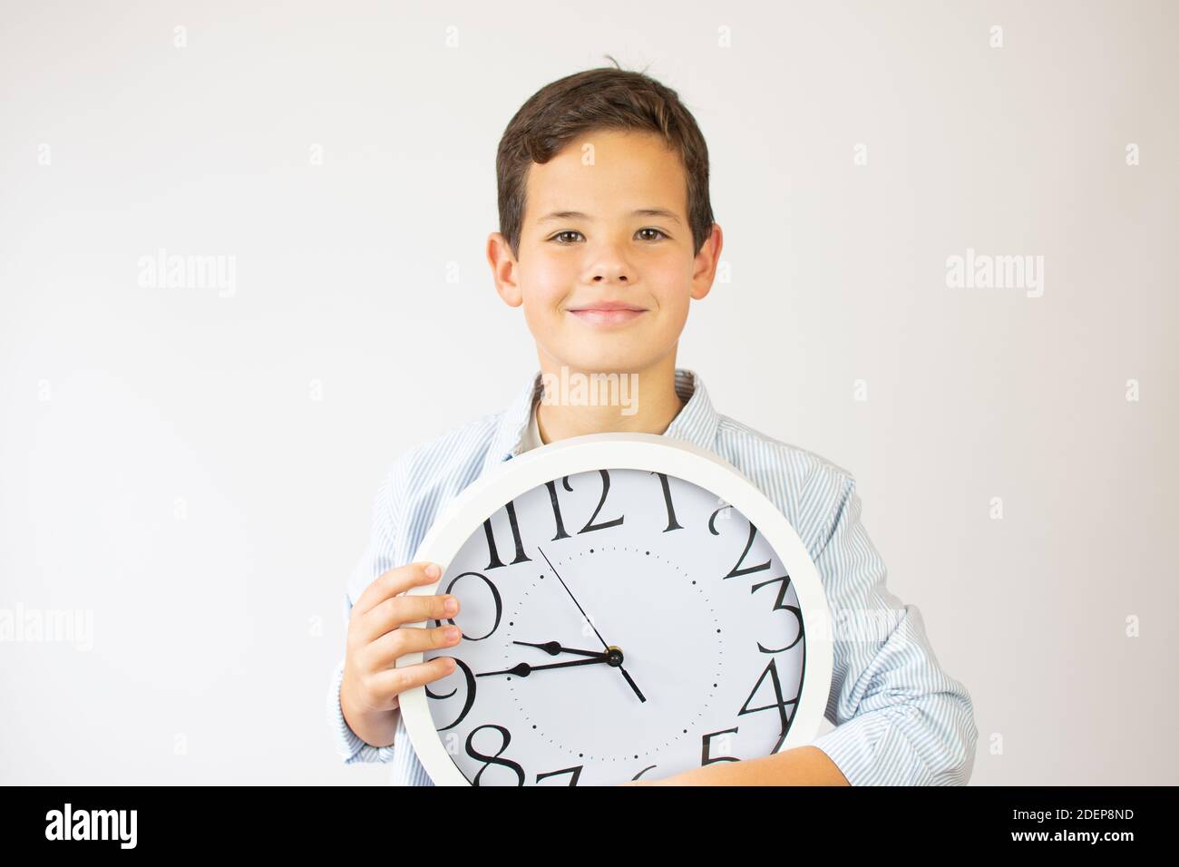 Portrait of a young boy holding a clock isolated on white background ...