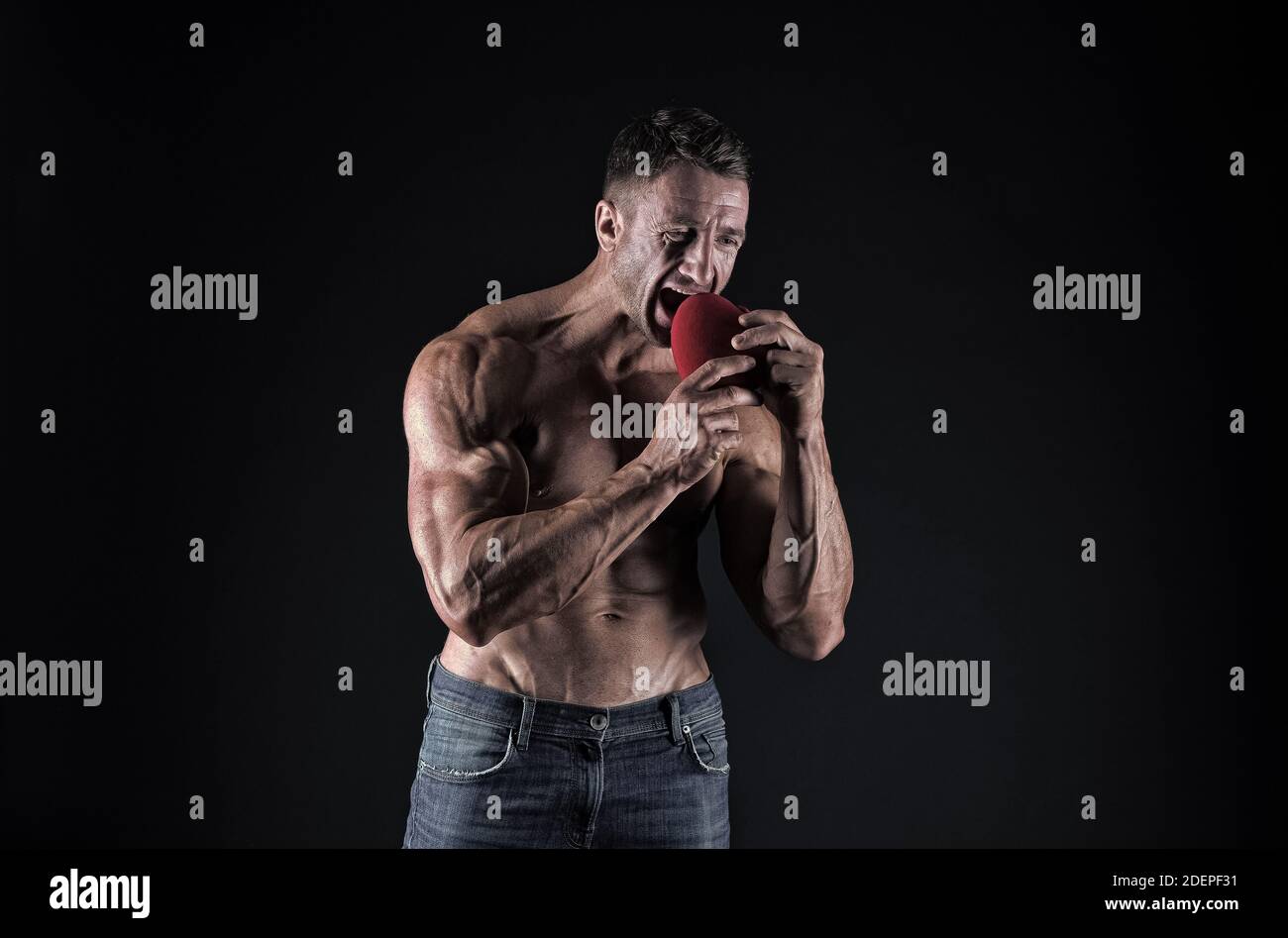 Eating heart healthy diet. Bodybuilder pretend eating red heart ...