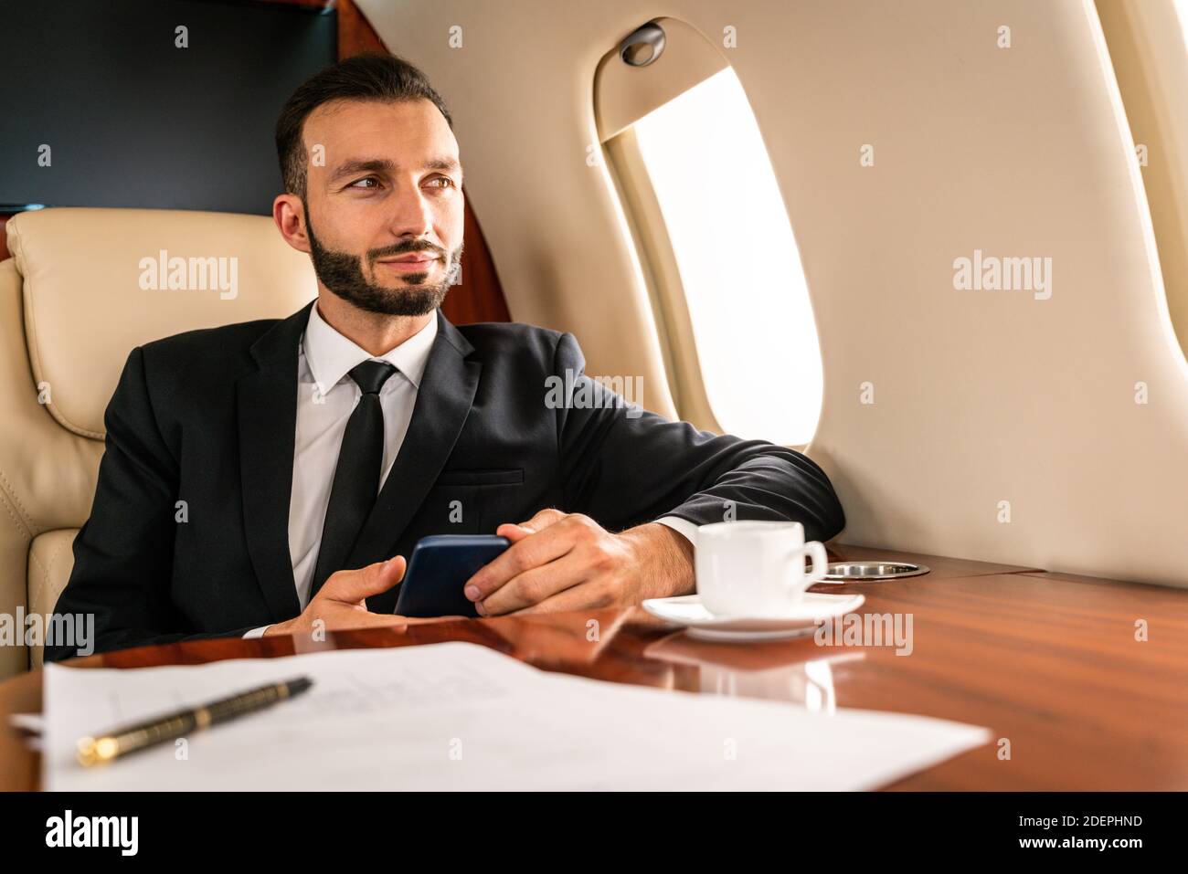 Handsome businessman wearing elegant suit flying on exclusive private ...
