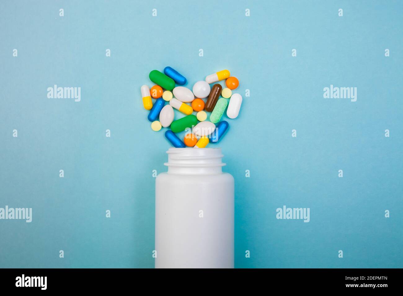 Multi-colored tablets and heart-shaped capsules, white bottle for ...