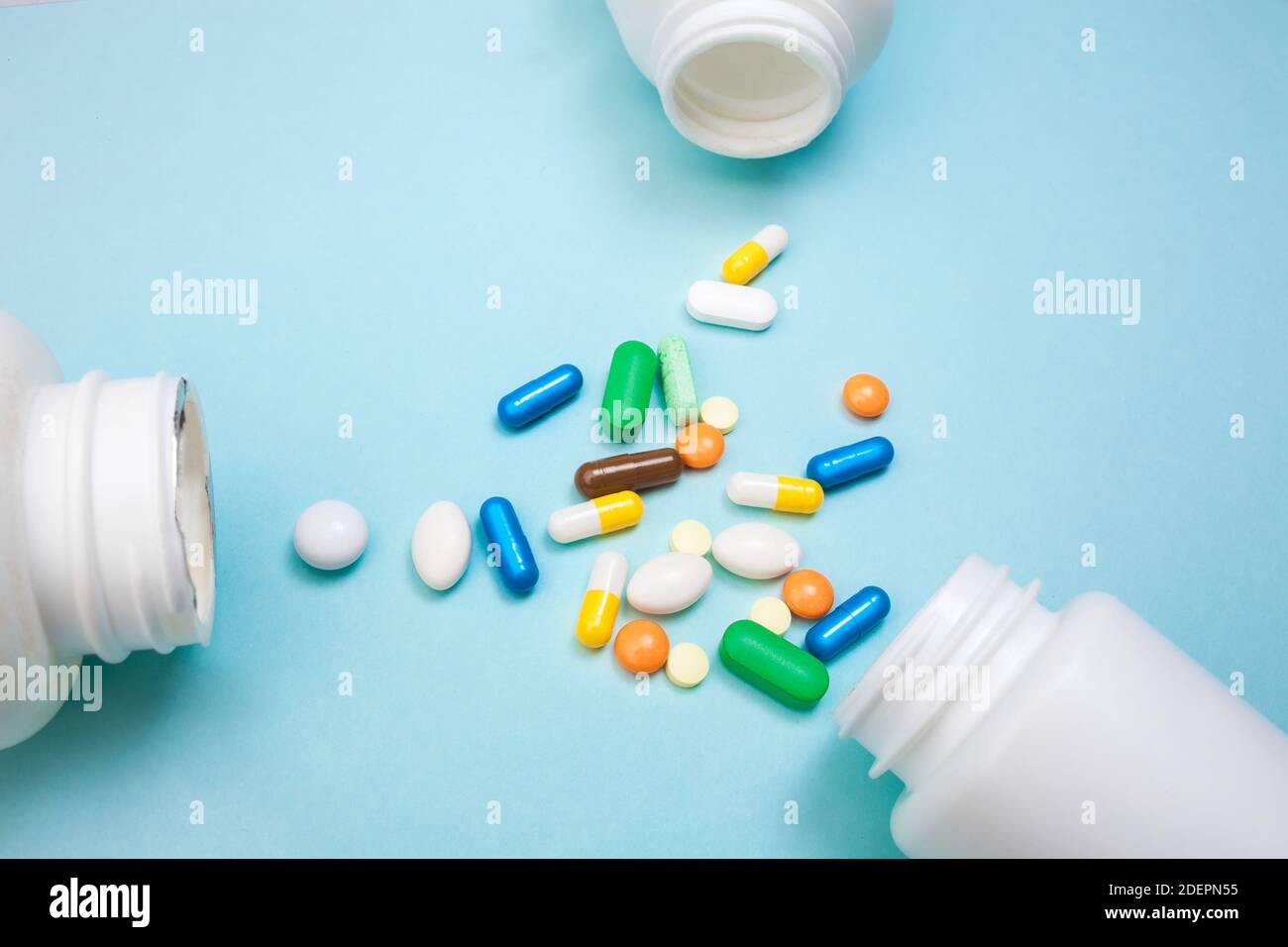 Multi-colored tablets and capsules, white bottle for tablets ...