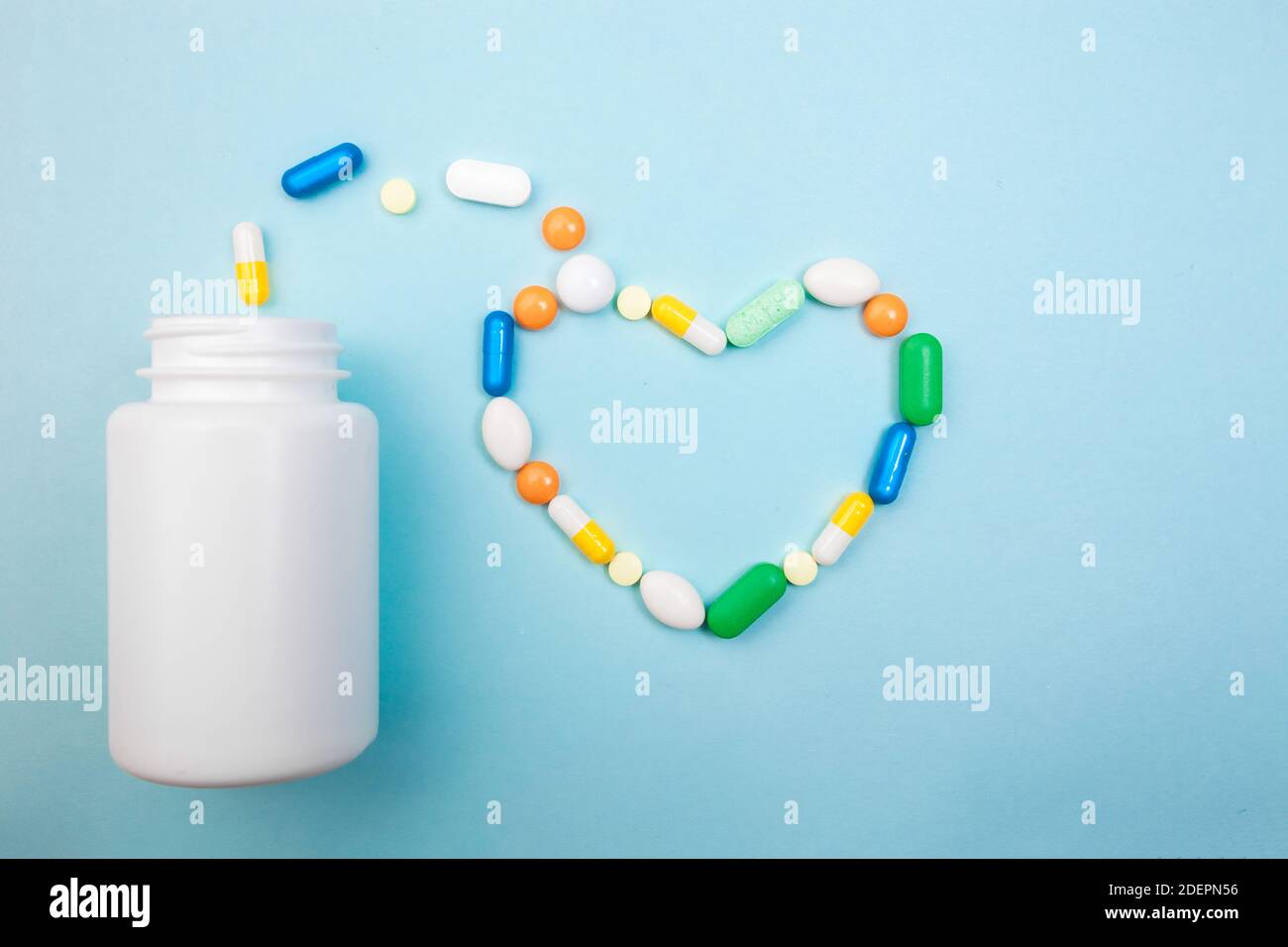 Multi-colored tablets and heart-shaped capsules, white bottle for ...