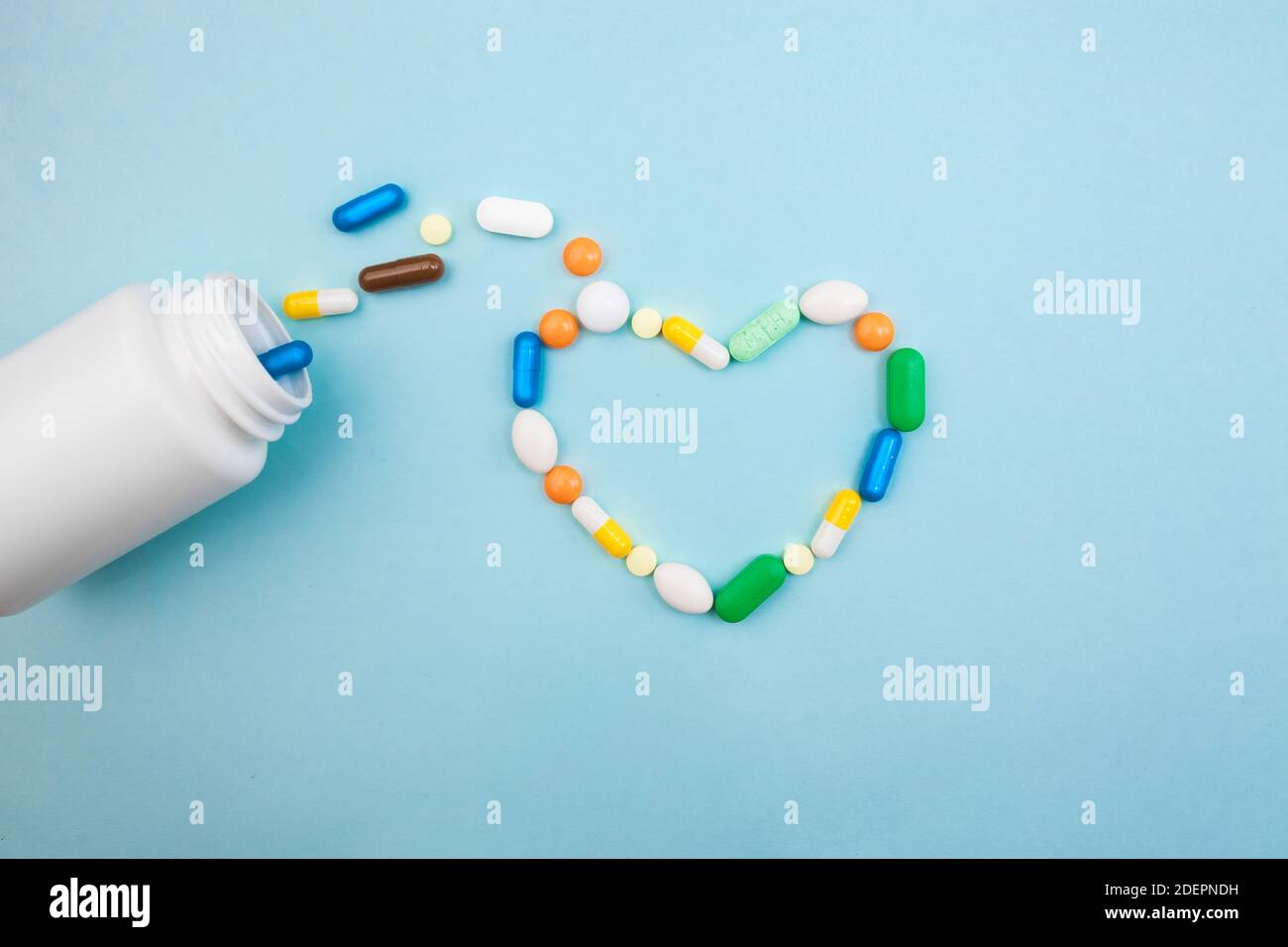 Multi-colored tablets and heart-shaped capsules, white bottle for ...