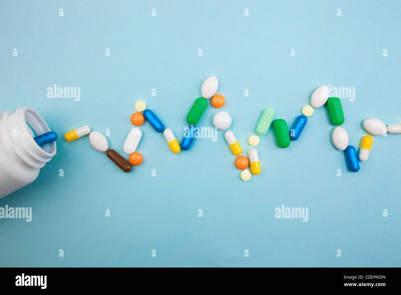 Multi-colored tablets and capsules in pulsation heartbeat white bottle ...