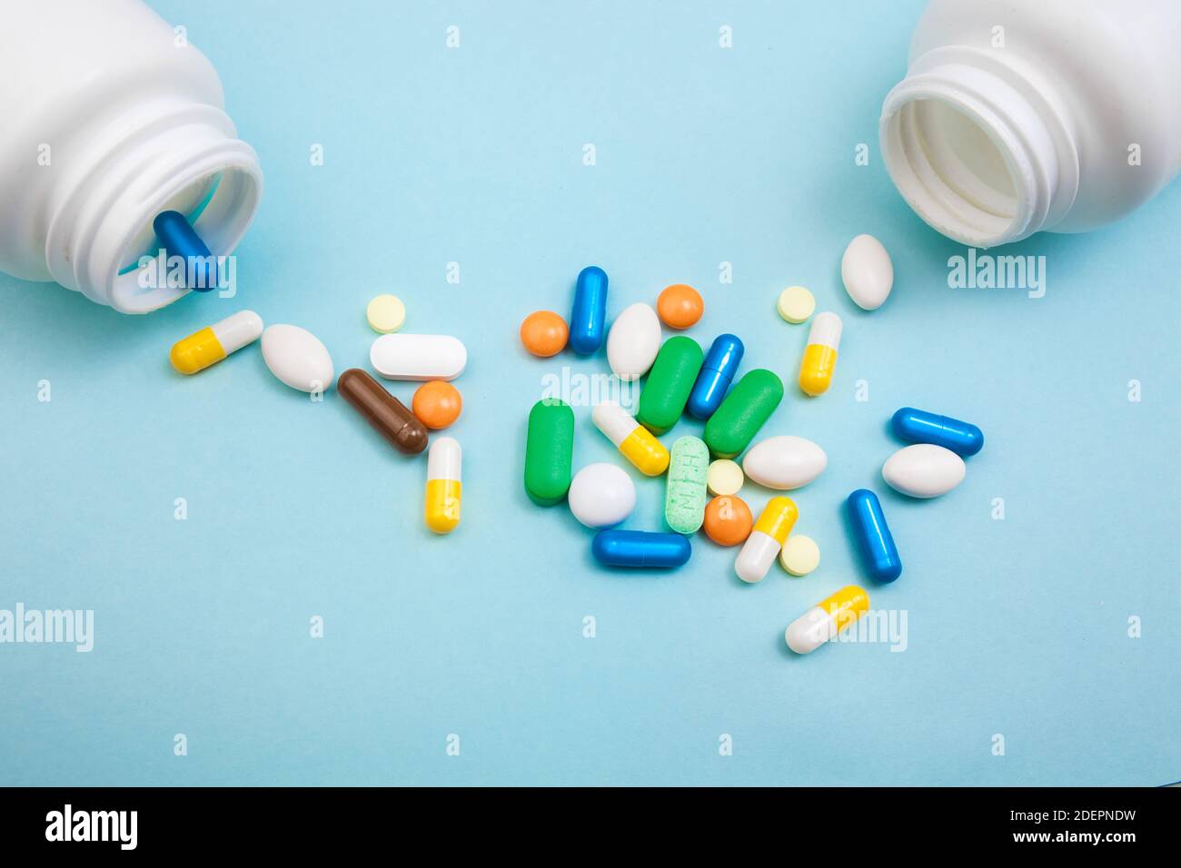 Multi-colored tablets and capsules, white bottle for tablets ...